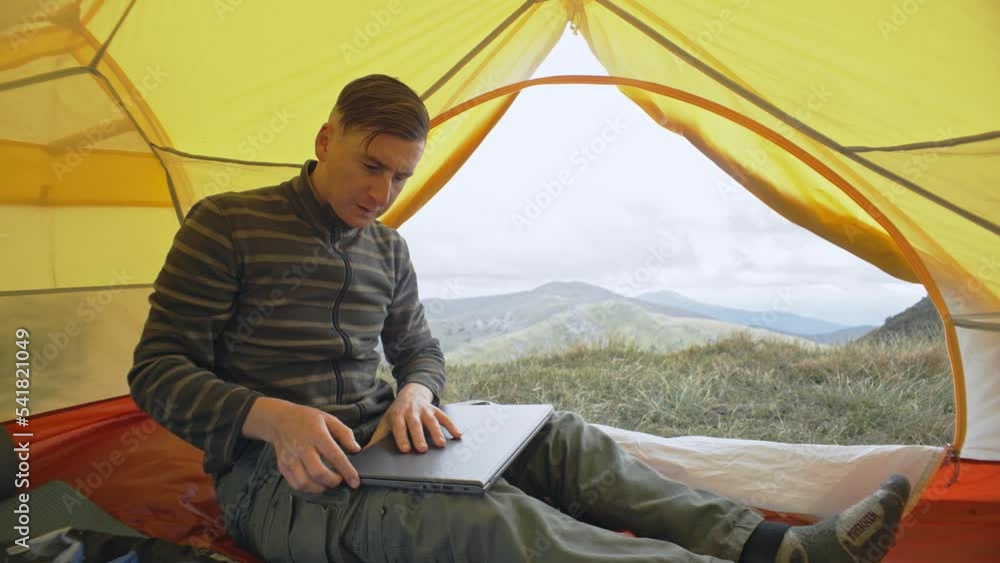 Vidéo Stock A man works on a laptop. Work remotely in the mountains, in ...