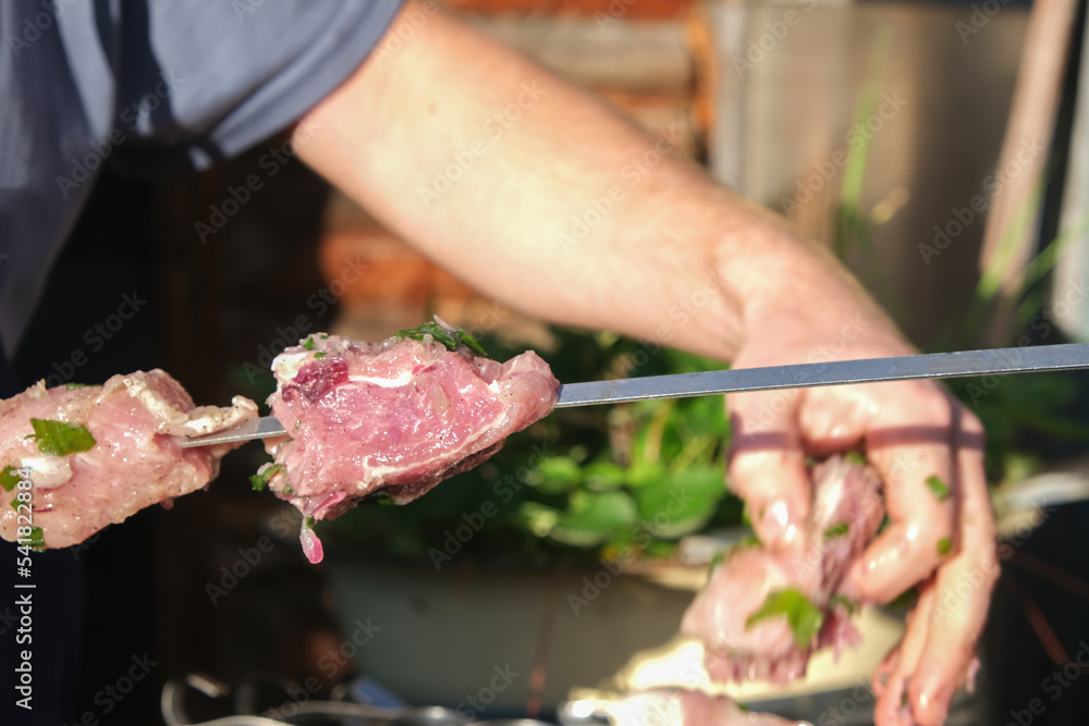 A man strands pickled meat on a skewer. A man puts meat on a skewer ...