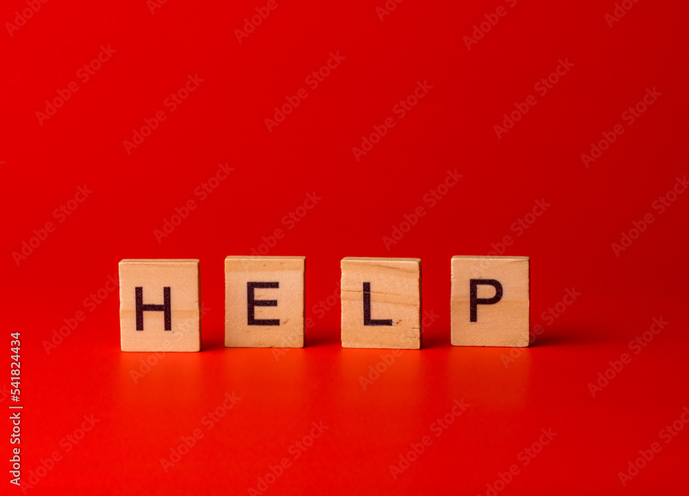 the word "help" written with letters on wooden chips, on a red ...