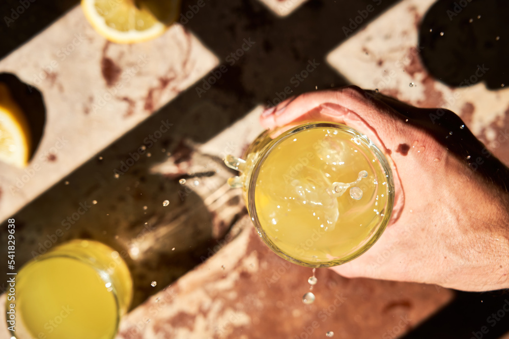 Unrecognizable man's hand holding a glass of fresh lemonade. Top view ...