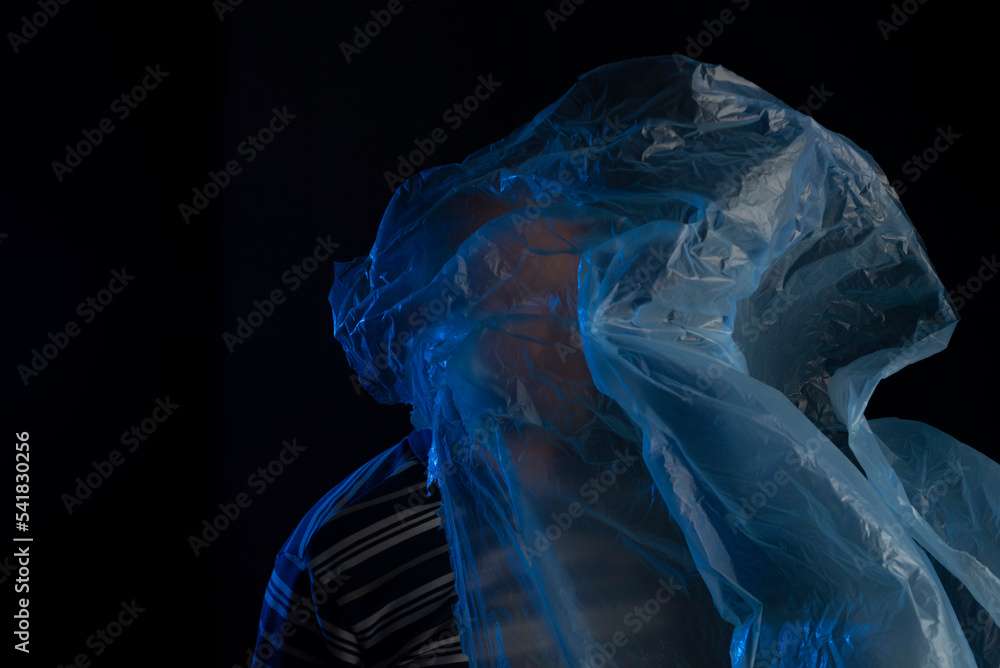 Mature man with a transparent plastic blue bag flying over his head and ...
