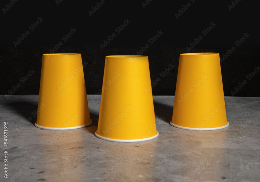 Three inverted yellow paper disposable cups. The concept of cheating ...