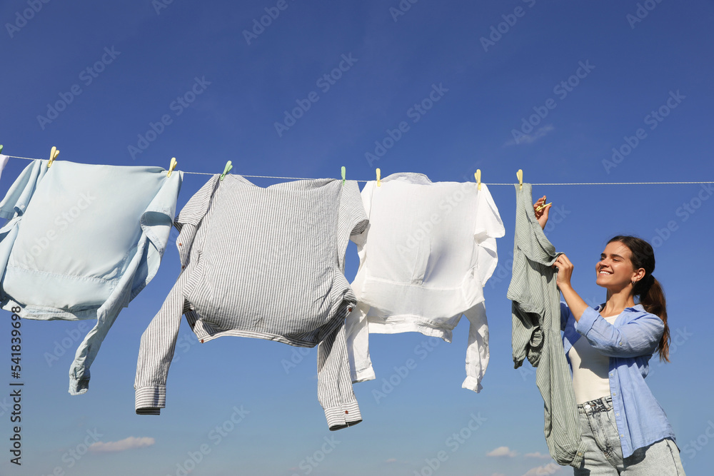 Woman hanging clothes with clothespins on washing line for drying ...