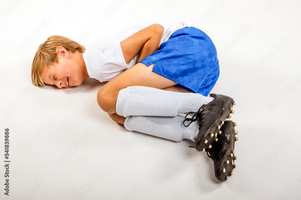 Crying injured boy soccer player lying on the ground after hit in the ...
