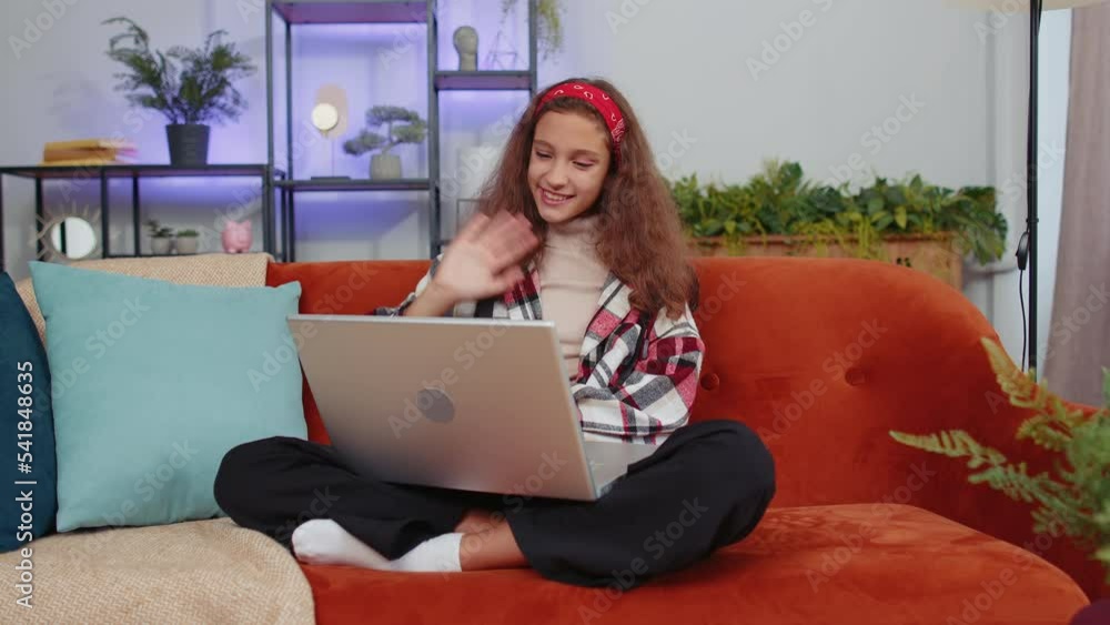 Preteen girl sitting on couch, looking at camera, making video webcam ...