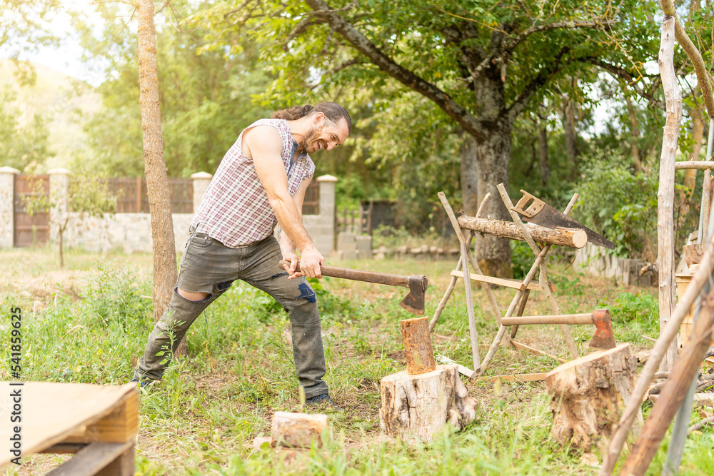 Man chopping wood with an axe outdoors Photos | Adobe Stock