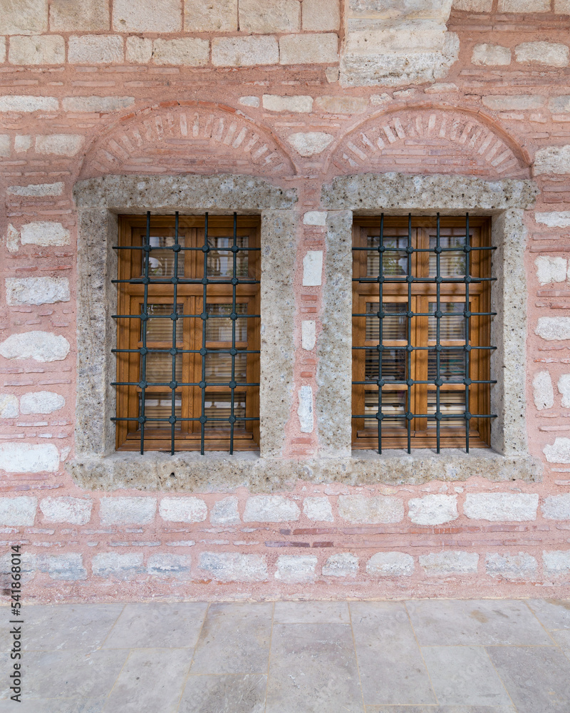 Two adjacent wooden arched windows in an old red and white stone bricks ...