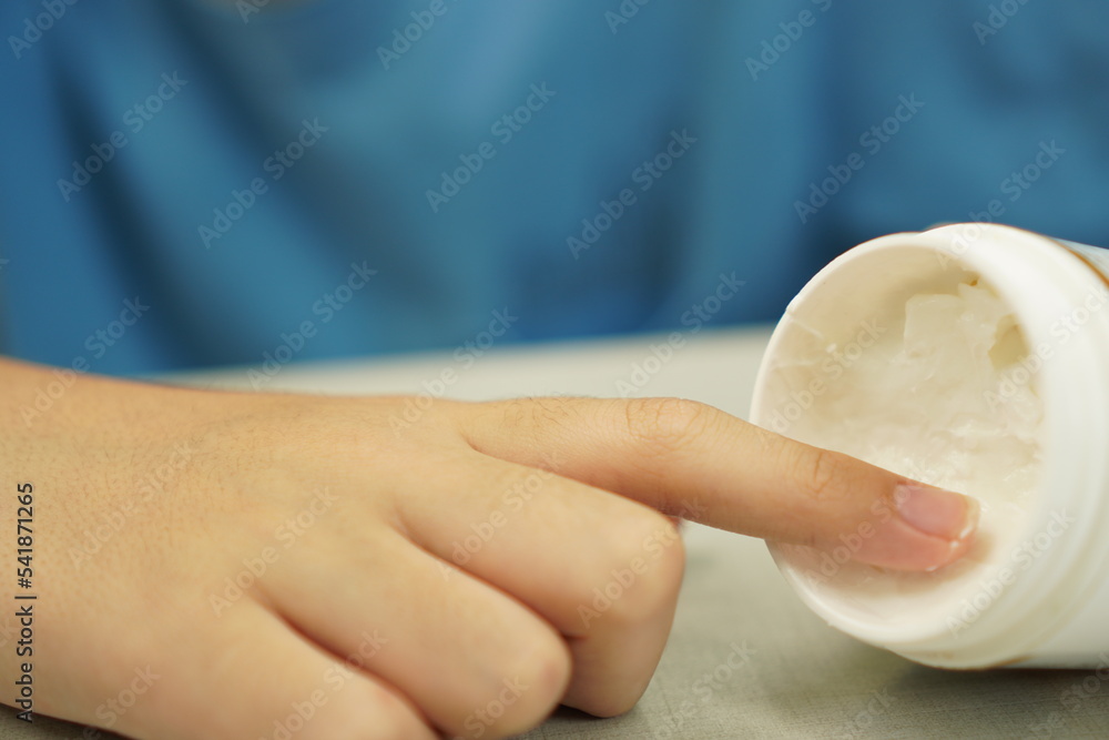 Skin care: The picture shows the use of a finger to reach the jar of ...