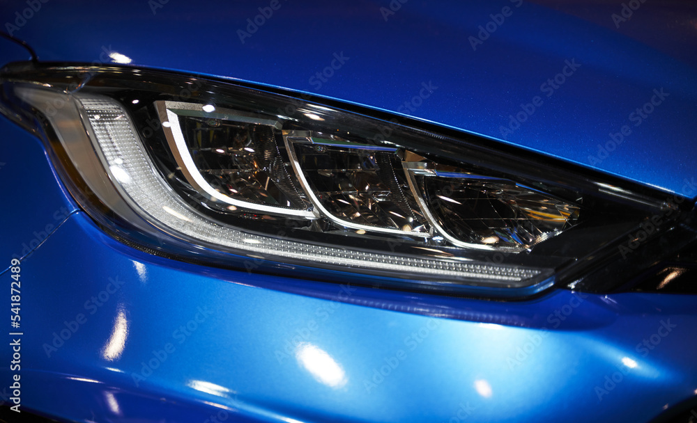 a blue and silver car with the lights on it in the dark background ...