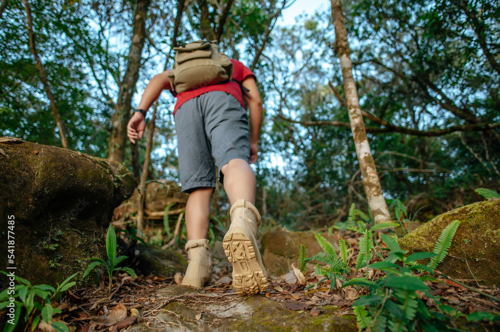 back of young trekking man with backpack walking up steep slope Stock ...