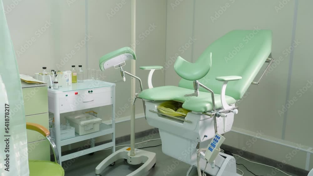 Gynecological chair in medical office moving up. consulting ...