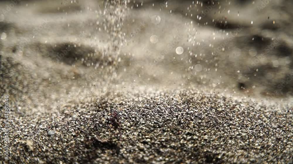 sand pouring slowly, against the background of golden bokeh, sunset ...