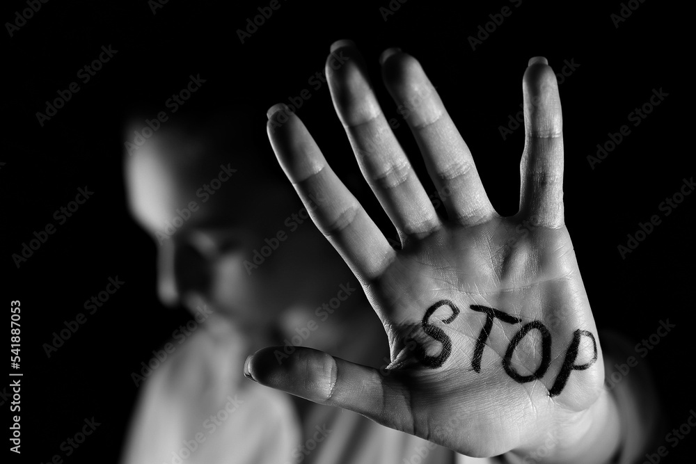 Woman with word Stop written on hand against black background, closeup ...