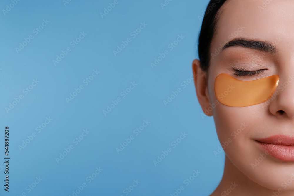 Beautiful young woman with under eye patch on light blue background ...