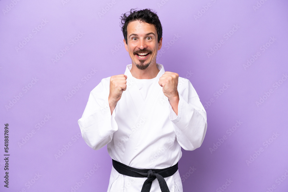 Young caucasian man doing karate isolated on purple background ...