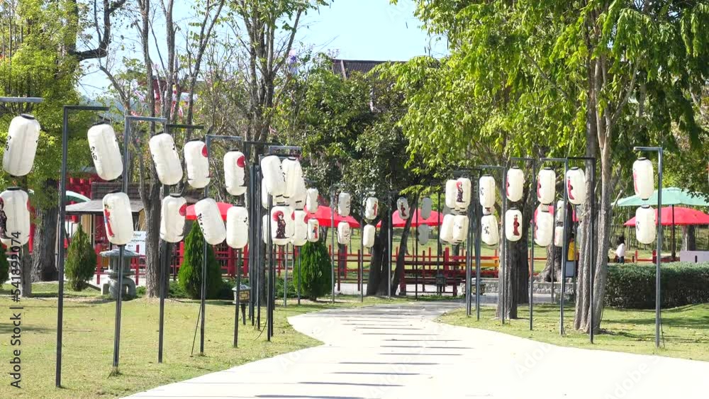 Traditional Japanese paper lanterns hang near pathway in thematic park ...