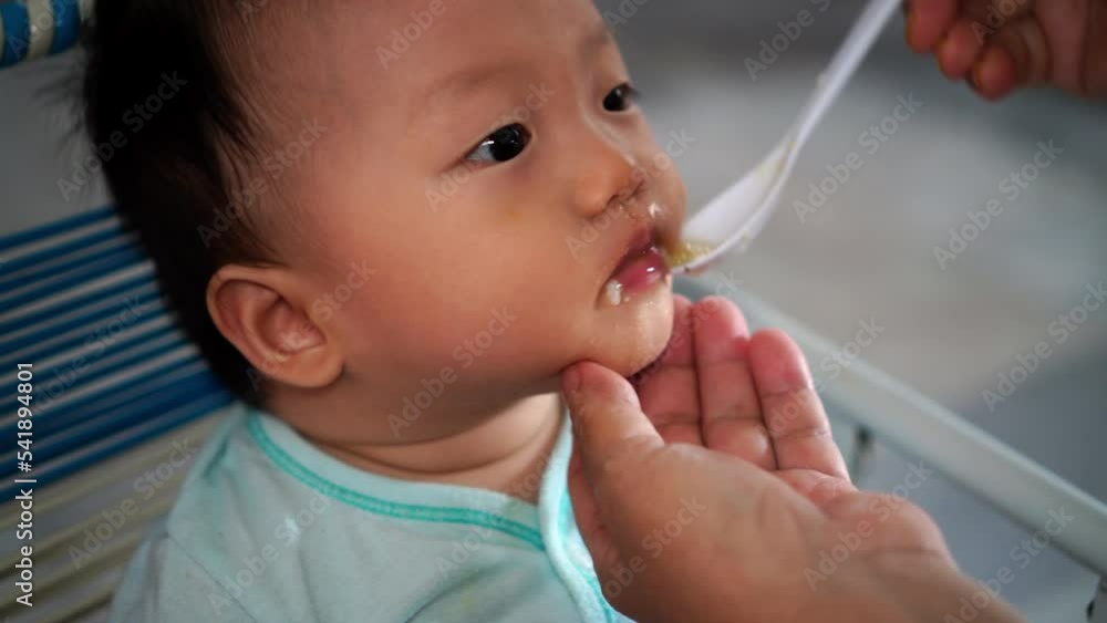 Mother use hand hold the chin of baby to feed porridge Stock Video ...