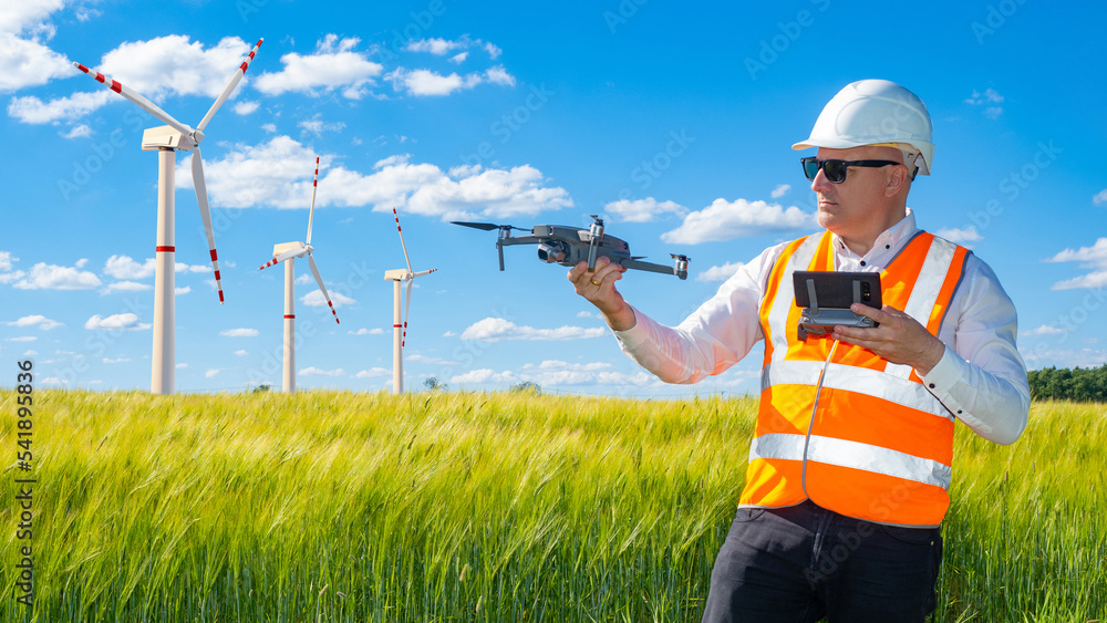 Green energy. Man with drone. Wind energy company employee. Windmills ...