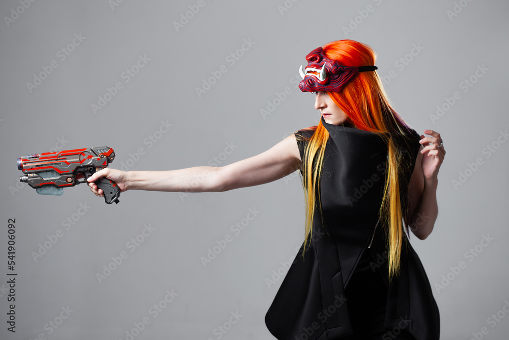 Cyborg mercenary in Asian demon mask, young woman with bright orange ...