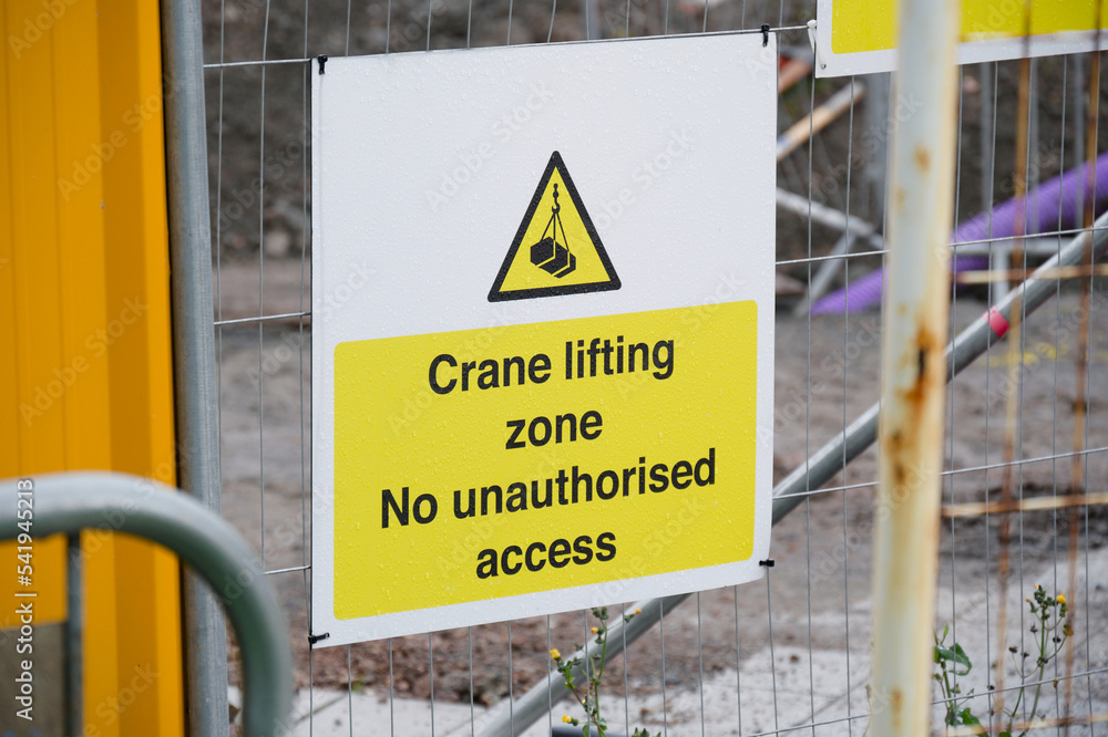Crane lifting safety sign on construction site fence Stock Photo ...