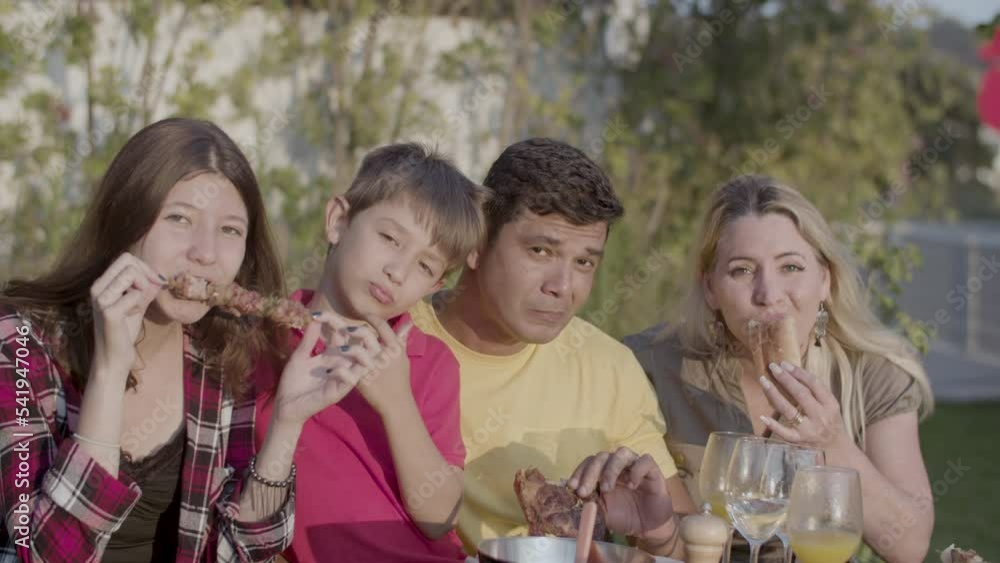 Portrait of happy family eating meat at barbecue party. Teenage girl ...