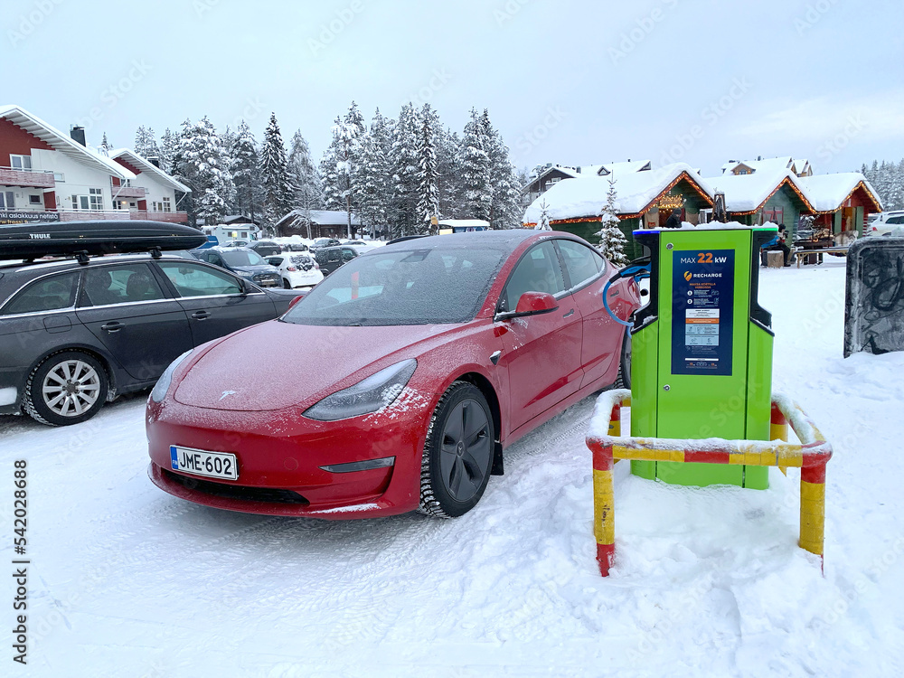 Tesla red passenger electric car replenishes battery at charging ...