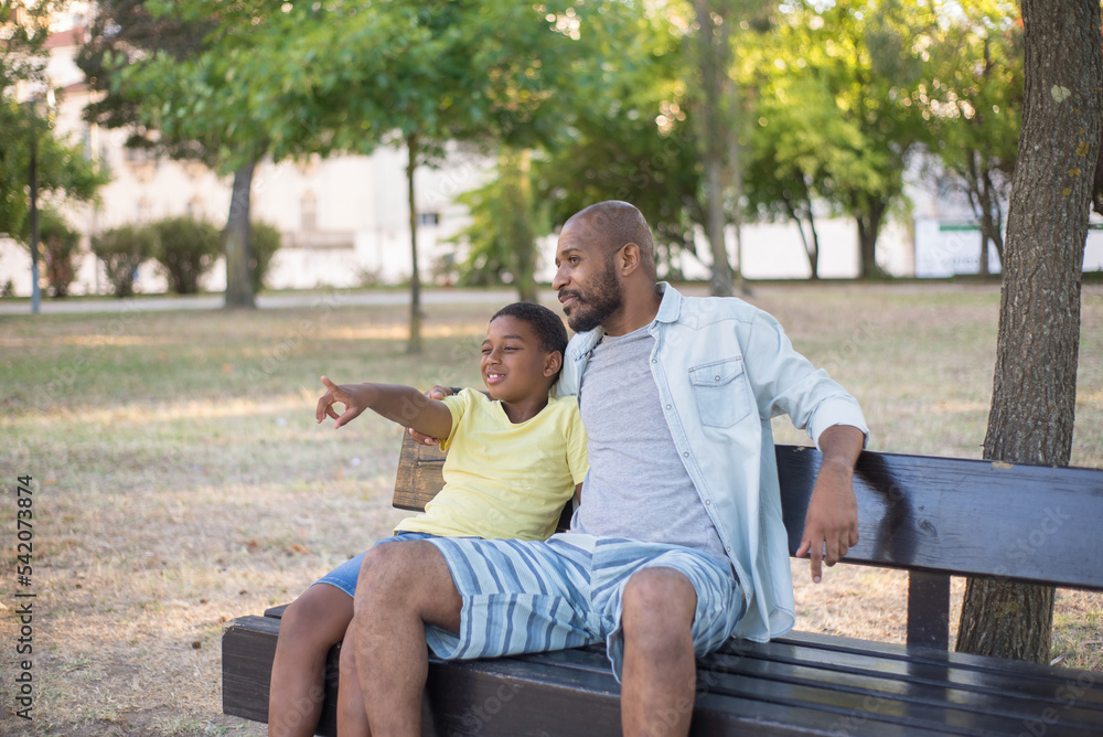 Portrait of bald man and boy having good day in park on bench. Bearded ...