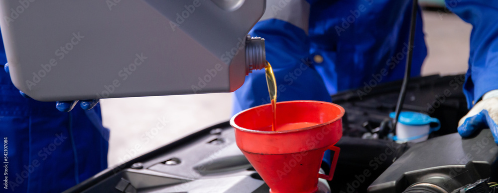 Closeup hands of mechanic man pouring motor oil in engine car in the ...