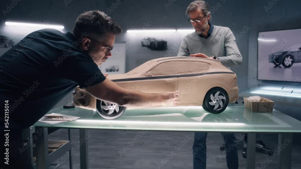 Two male automotive designers creating futuristic plasticine clay model ...