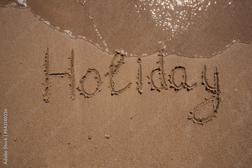 Inscription. The word holiday on the sand, by the sea and the wave ...