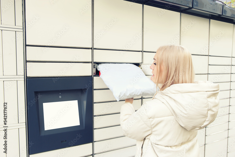 Blonde woman put the parcel in the self-service mail terminal. Parcel ...