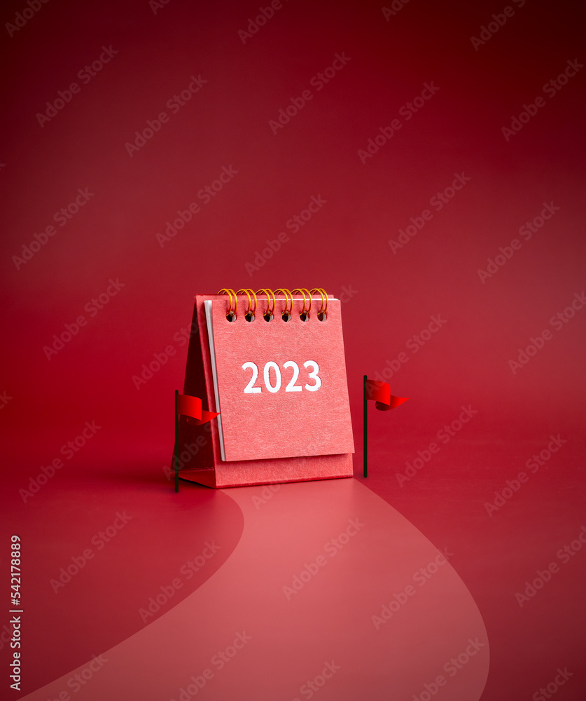 2023 year small red desk calendar standing between finish flags on road ...