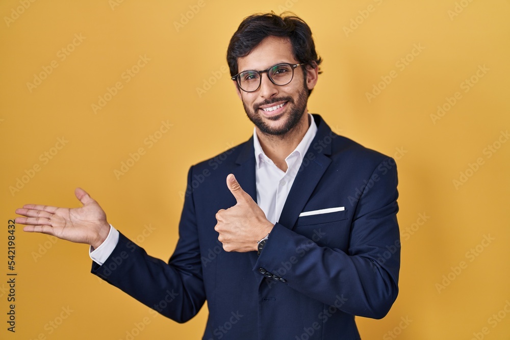 Handsome latin man standing over yellow background showing palm hand ...