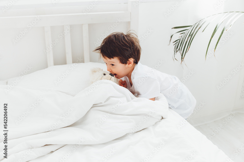 Happy little Asian boy cleans his room and folds a blanket in the ...