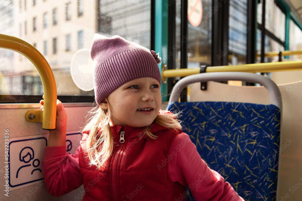 Pretty little girl rides bus of public modern transport looks out ...