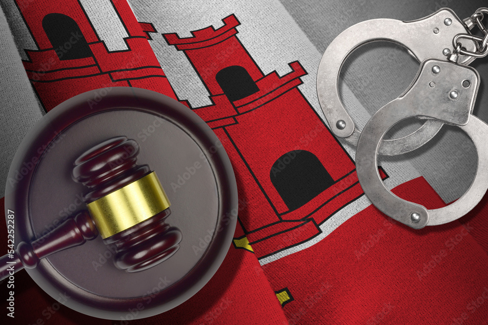 Giblartar flag with judge mallet and handcuffs in dark room. Concept of ...