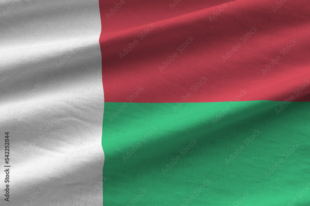 Madagascar flag with big folds waving close up under the studio light ...
