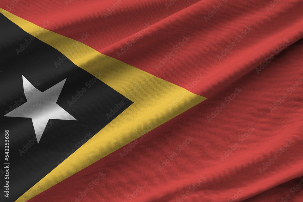 Timor Leste flag with big folds waving close up under the studio light ...