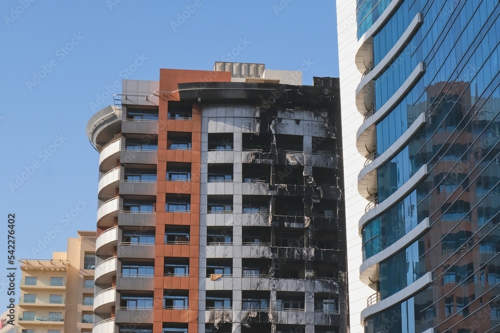 Fire insurance. Charred burnt residential high-rise building wall after ...