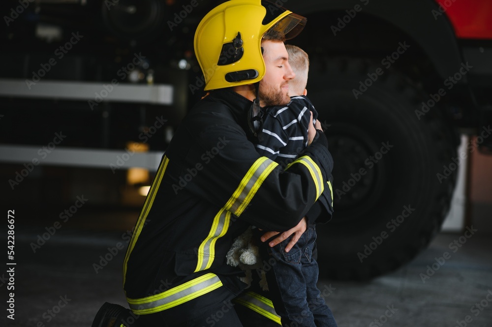Portrait of rescued little boy with firefighter man standing near fire ...