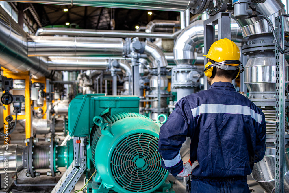 Refinery worker standing by gas fuel engines inside power plant ...