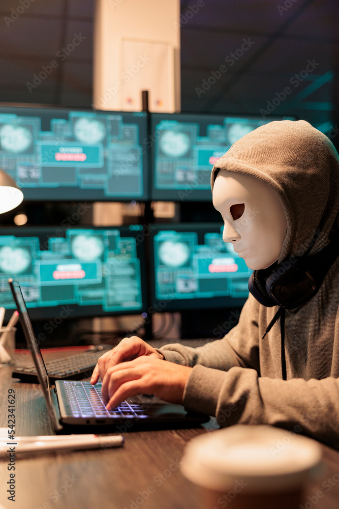 Scary male scammer wearing mask hacking database servers, hacker with hood breaking into ...