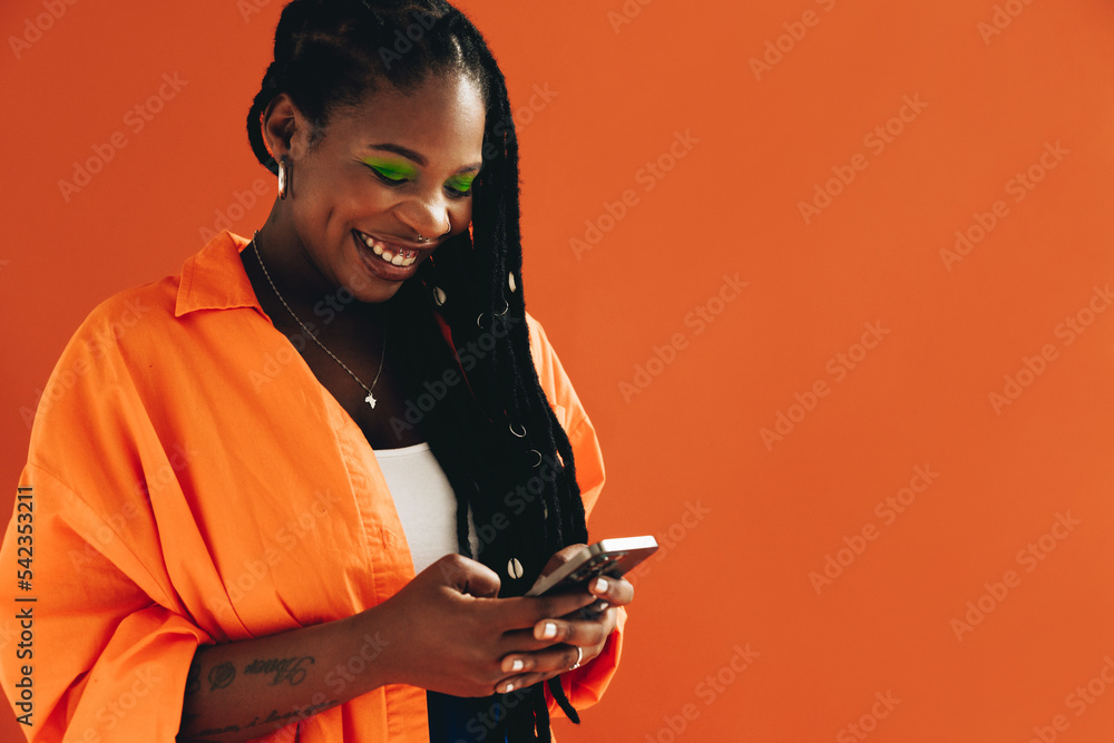 Smiling black woman sending a text message on her smartphone in a ...