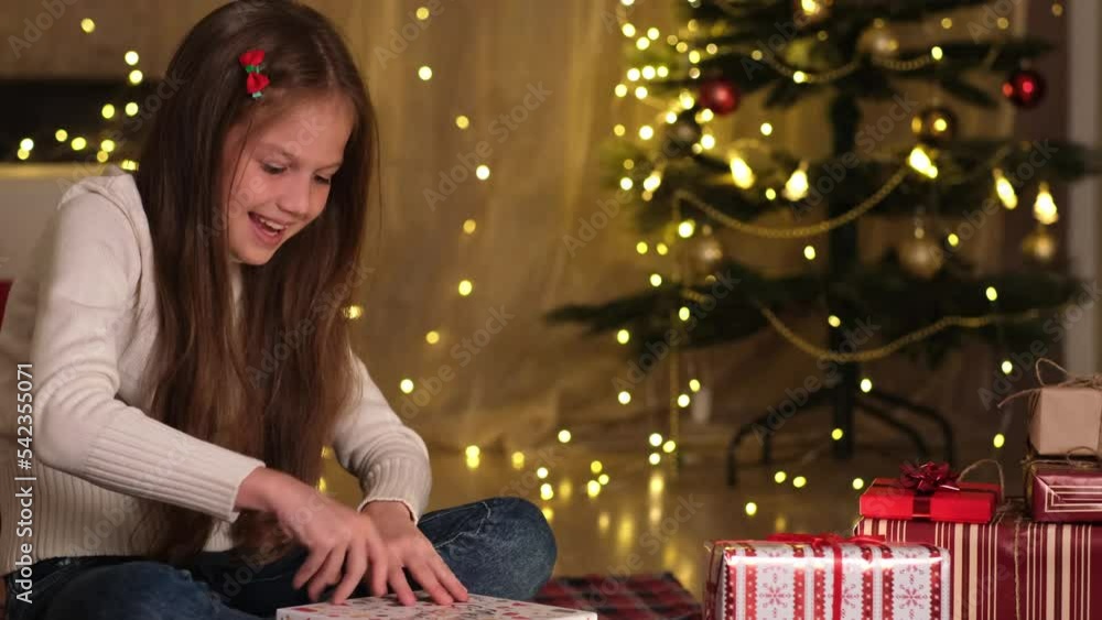 Little girl opening Christmas gift in decorated room and gets upset ...