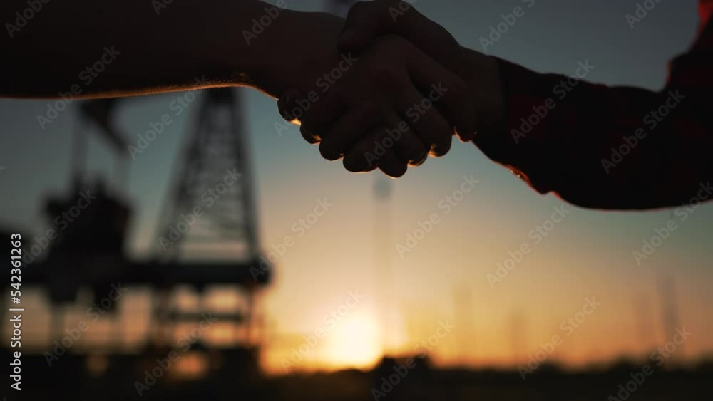 Oil pump. Engineers handshake. Corporate contract. People in helmets ...