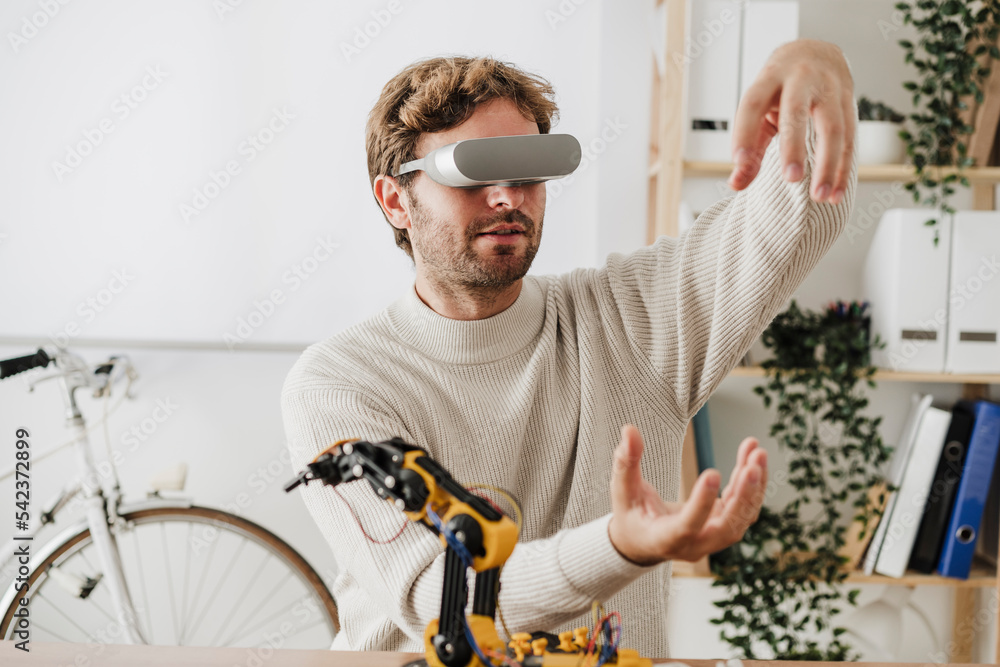 Engineer with futuristic goggles working on model of robotic arm in ...