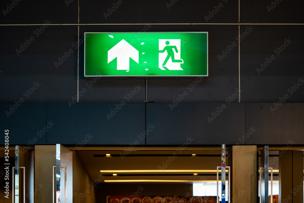 Big Emergency fire exit sign is placed on the black wall over the door ...