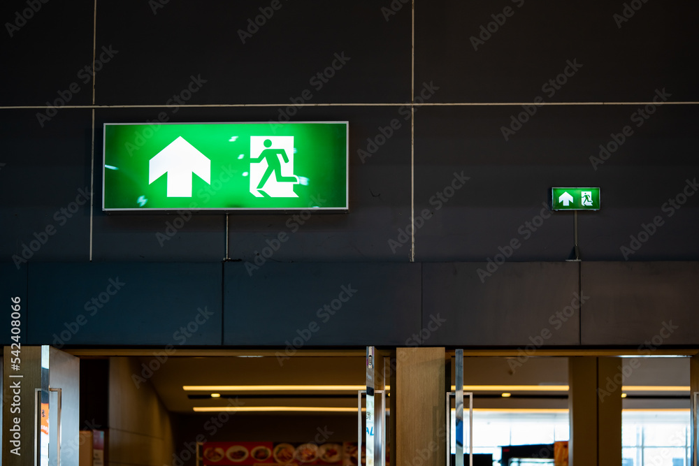Big Emergency fire exit sign is placed on the black wall over the door ...