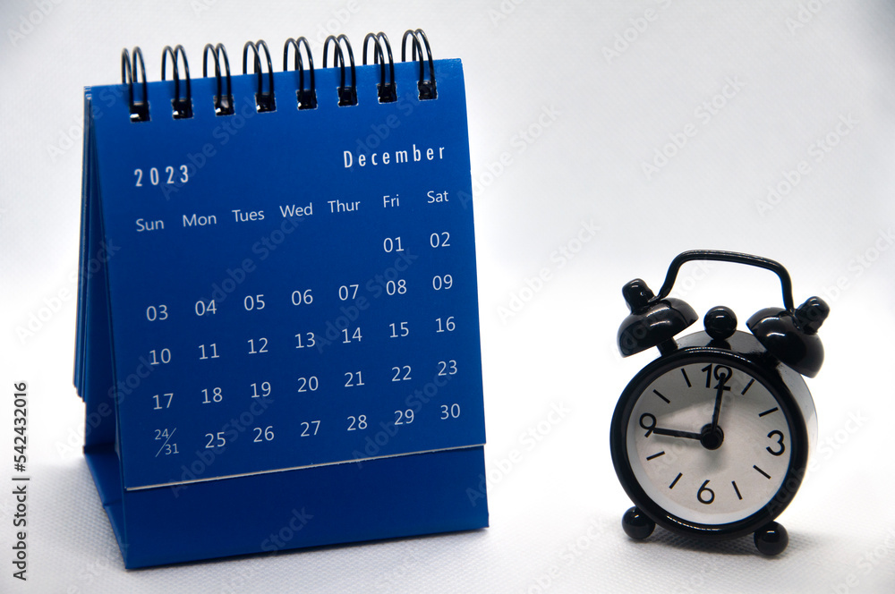 Alarm clock pointing at 9 o'clock with December 2023 calendar on white ...