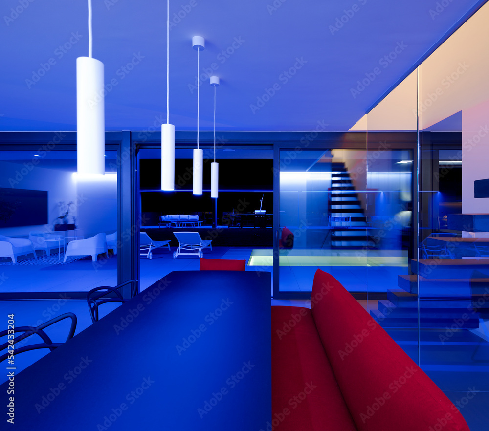 Front view living room with table and a red sofa lit by blue LEDs and ...